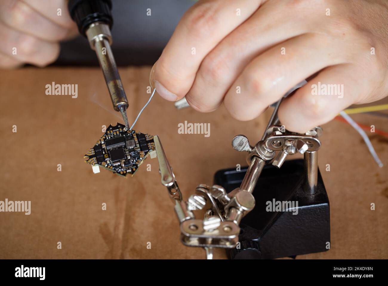 The hand holding the tin, a soldering iron solder the chip in place. a ...