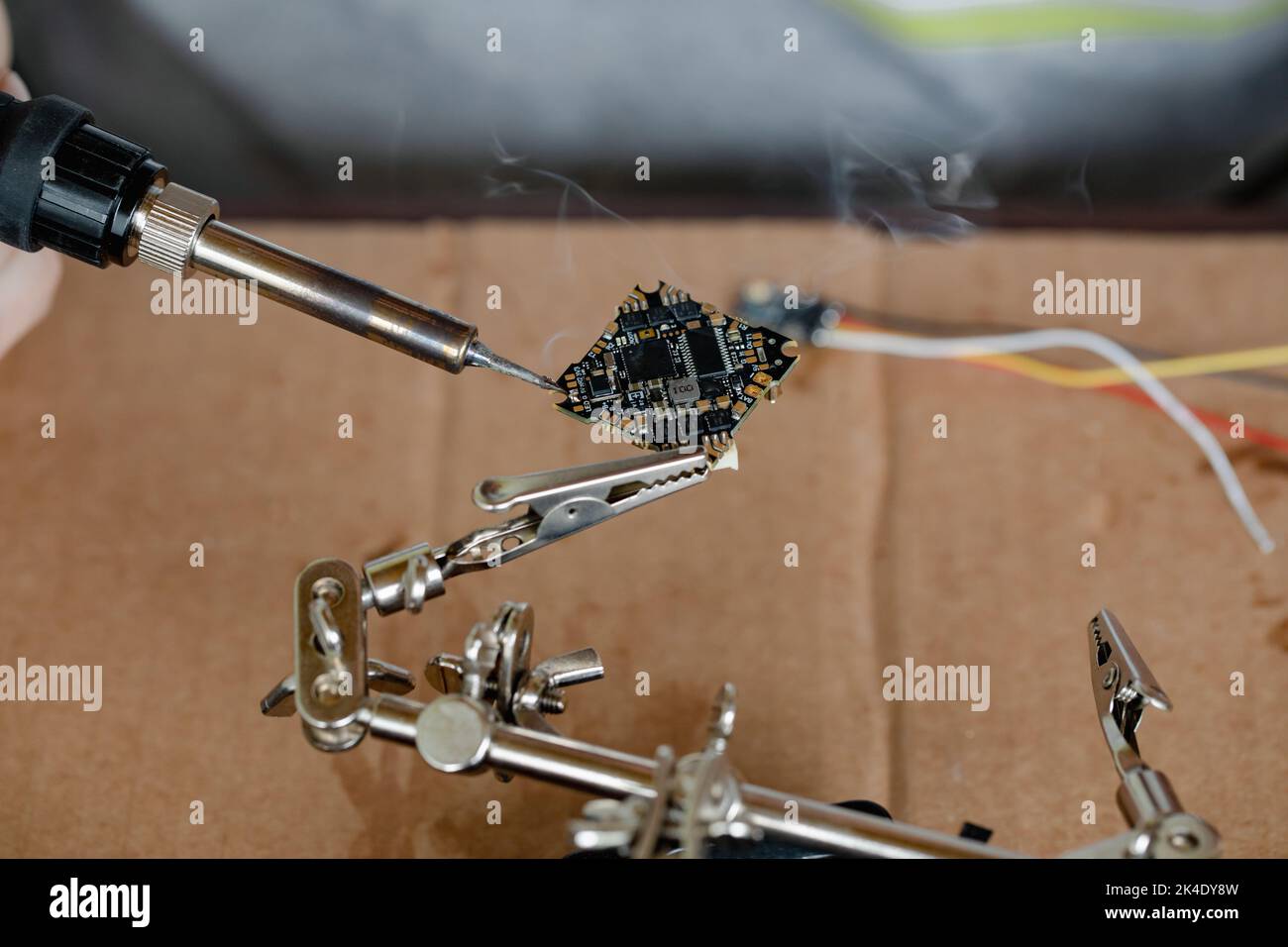 The hand holding the tin, a soldering iron solder the chip in place. a ...