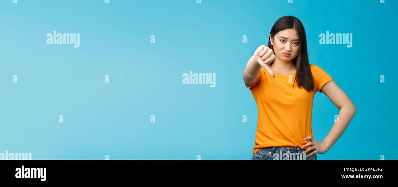 Disappointed and unsatisfied cute asian girl grimacing, showing thumb ...