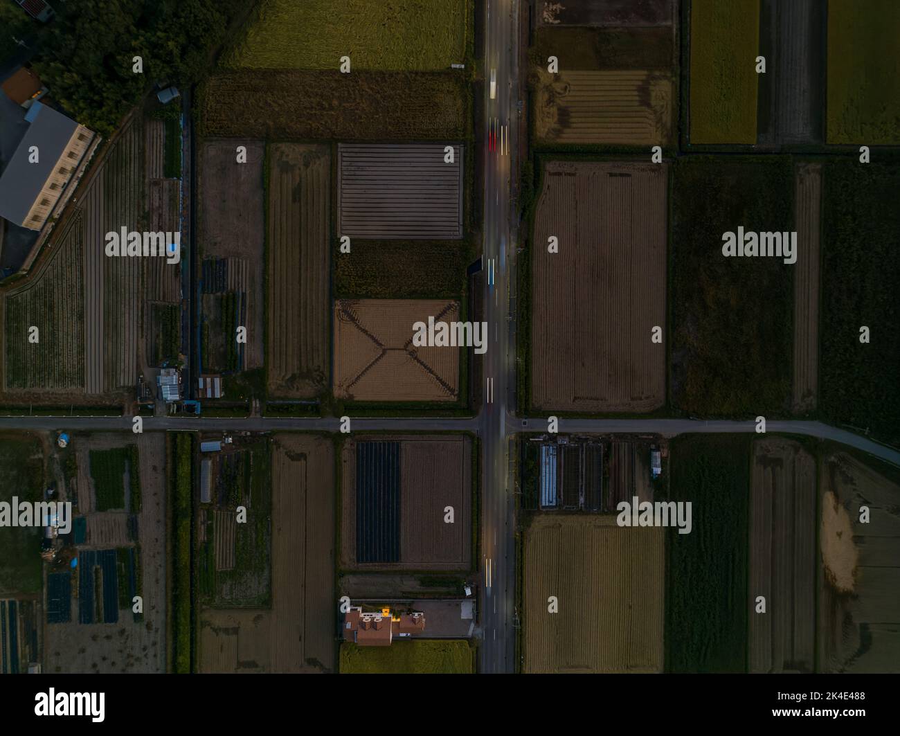Top-down aerial view of road by fields in quiet neighborhood at dusk ...