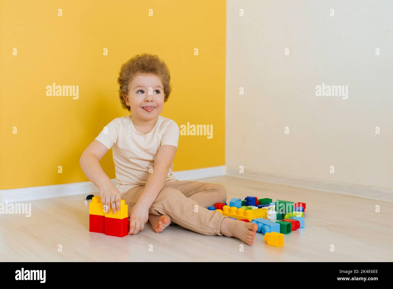 Cheerful happy kid is playing with toys. A boy builds a construction ...