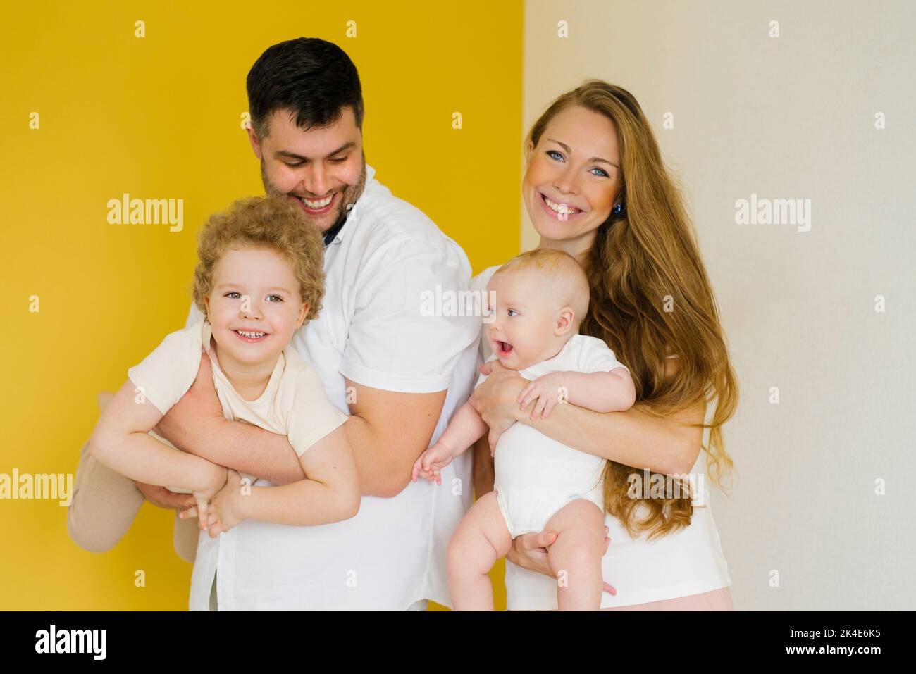 Father and mother stand side by side on a yellow background and hold ...