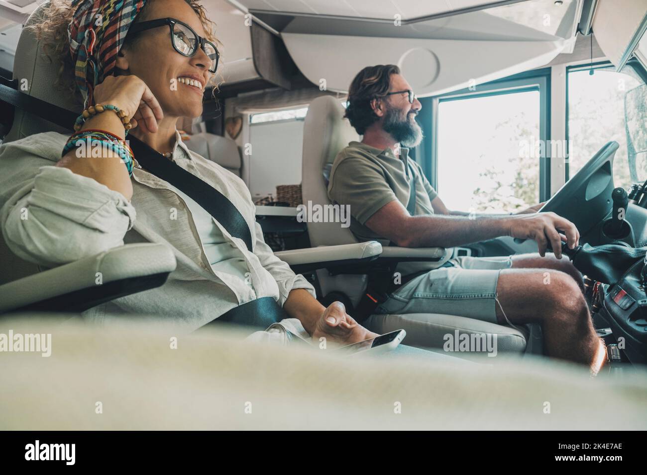 Side view of happy traveler couple inside camper van rv vehicle driving ...
