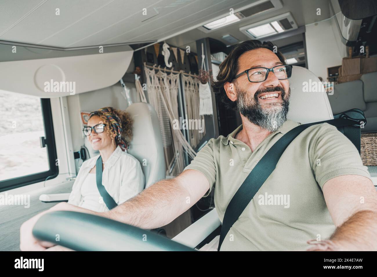 Inside view of happy adult couple driving and enjoying road trip in a ...