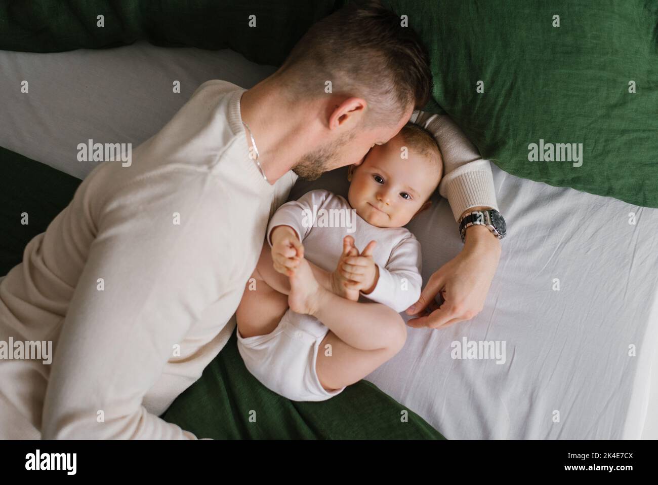 Young Caucasian dad hugs his baby son in the bedroom, happy family ...