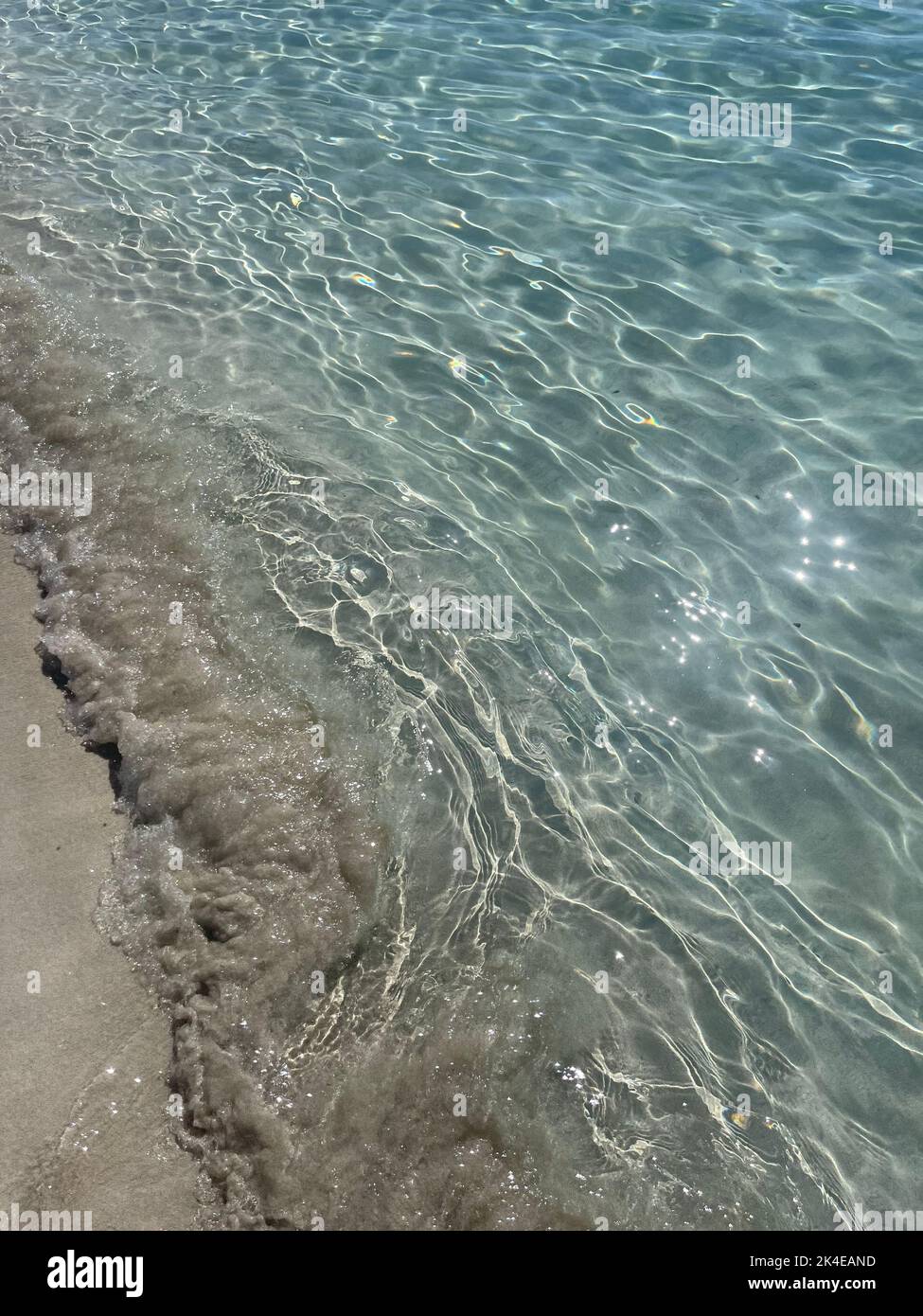 A vertical shot of a sandy beach against a blue sea on a sunny day ...