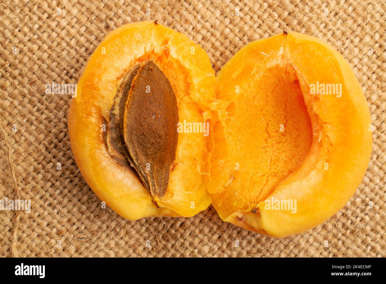 One yellow pineapple apricot cut in half, macro, on jute fabric, top ...