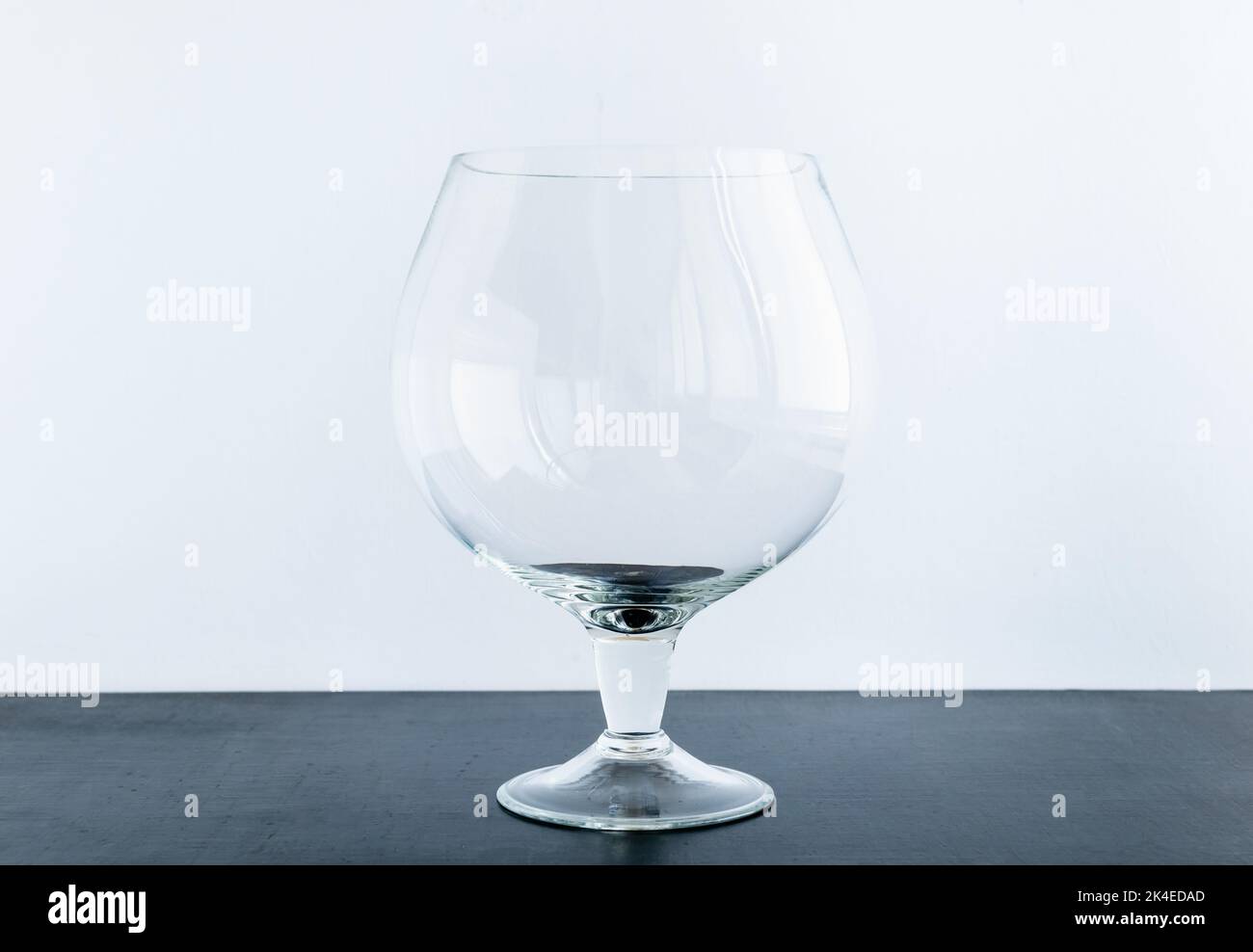 Transparent cognac glass on black table and on white background. For strong alcoholic drinks ...