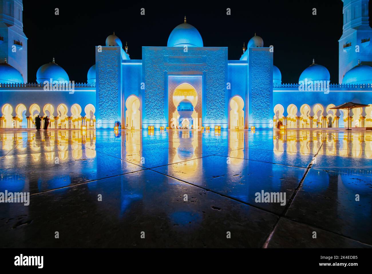 A Sheikh Zayed Grand Mosque at night illuminated with blue and gold ...