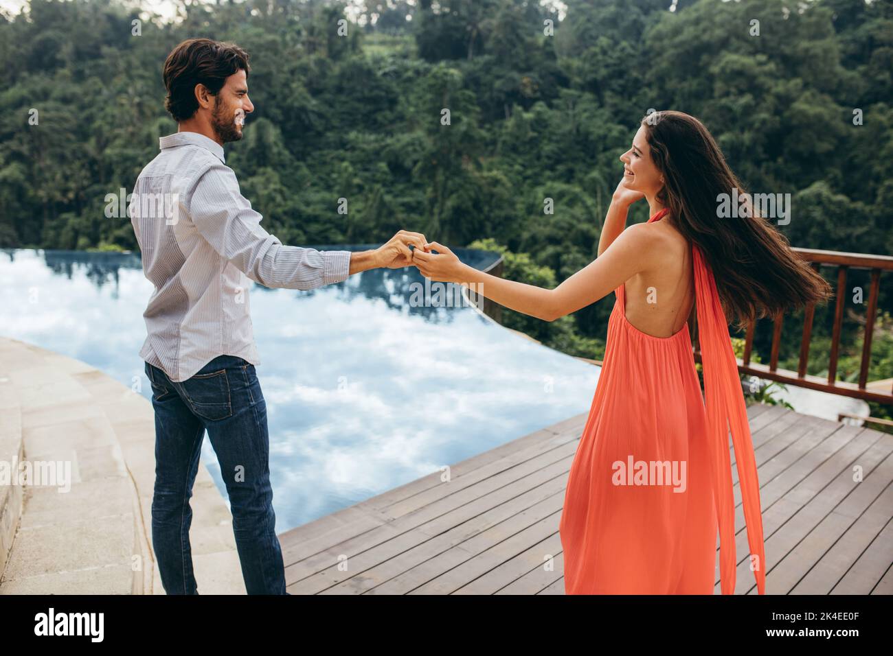 Portrait of caucasian couple dancing near swimming pool. Young man and ...