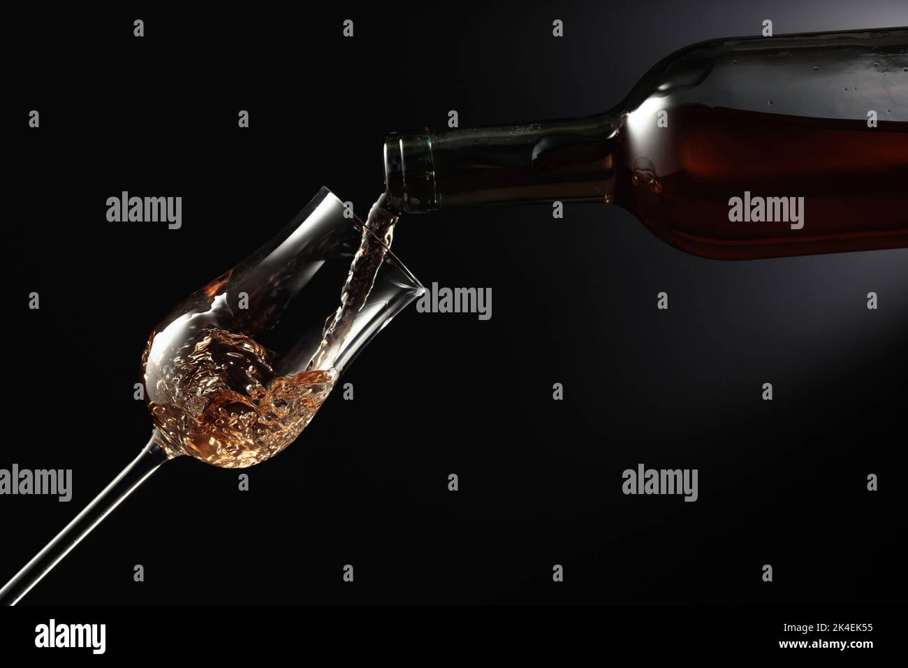 Glass of premium alcohol on a black background. The drink is poured ...