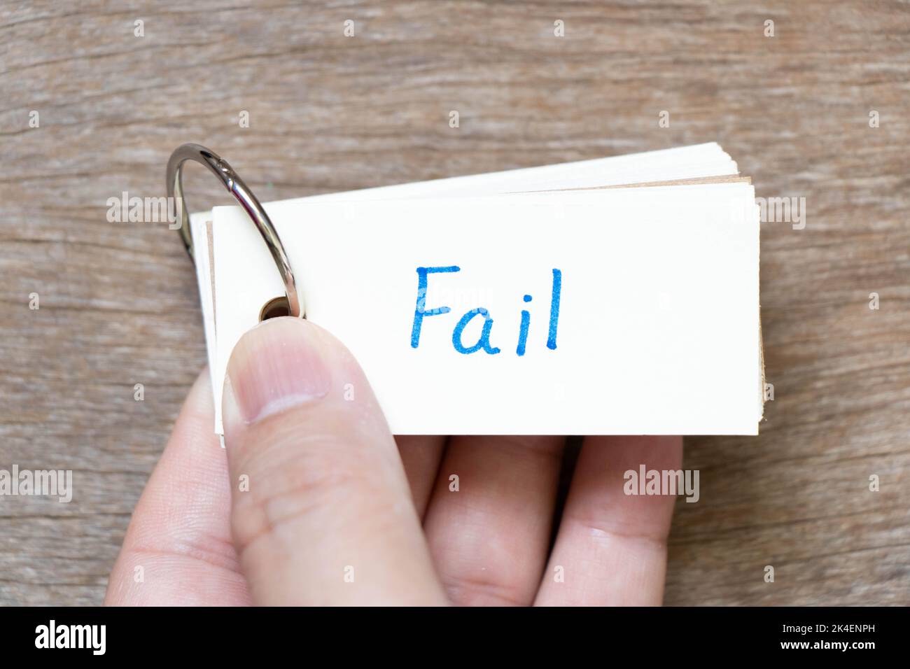 Hand hold flash card with handwriting in word fail on wood background ...
