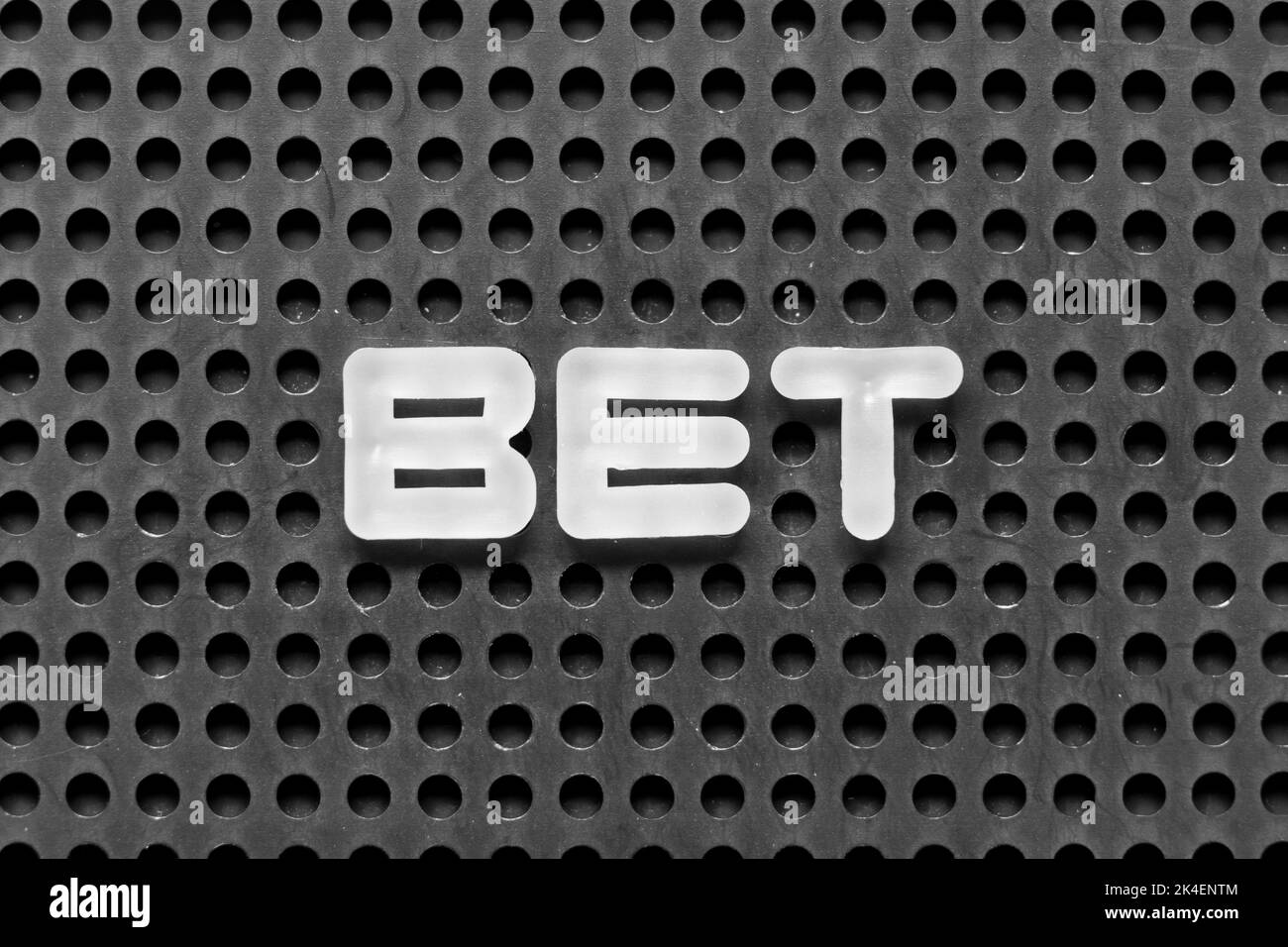 White alphabet letter in word bet on black pegboard background Stock ...