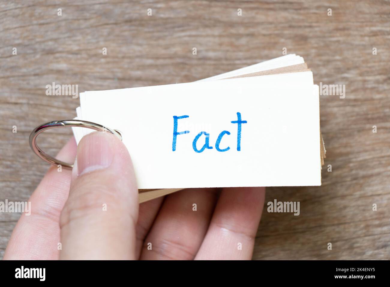 Hand hold flash card with handwriting in word fact on wood background ...