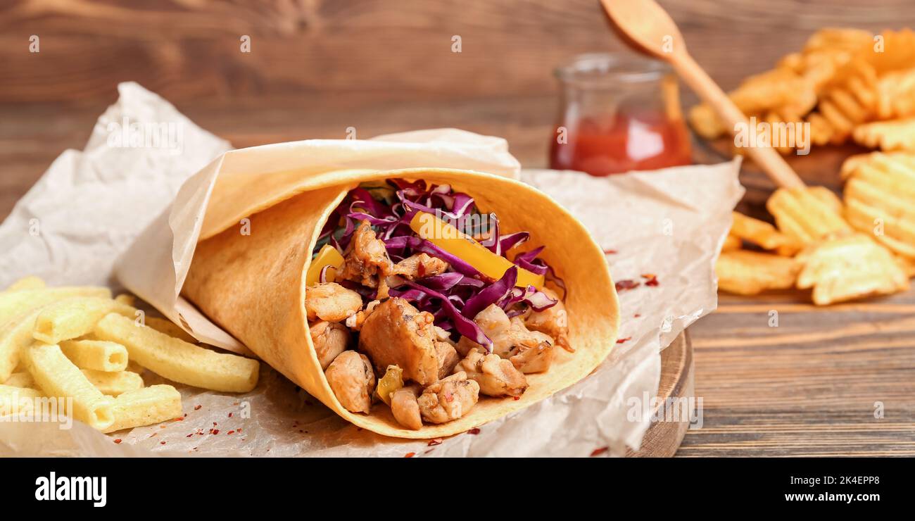 Tasty doner kebab, chips and french fries on wooden background, closeup ...