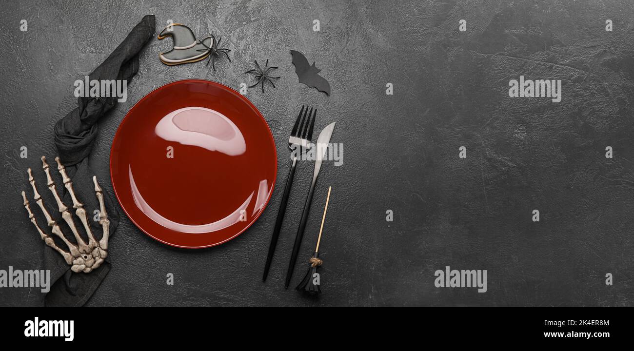 Table setting with scary Halloween decor on black background with space ...
