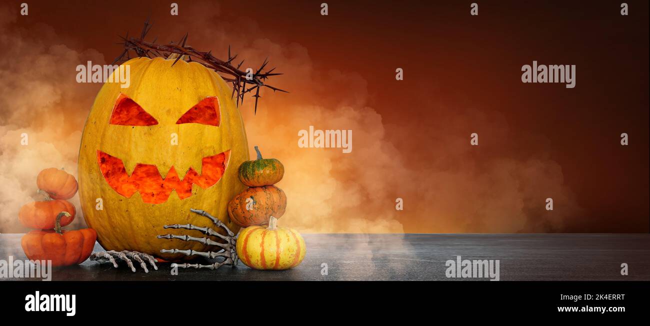 Creepy Halloween pumpkins with thorn wreath and skeleton hands on table ...