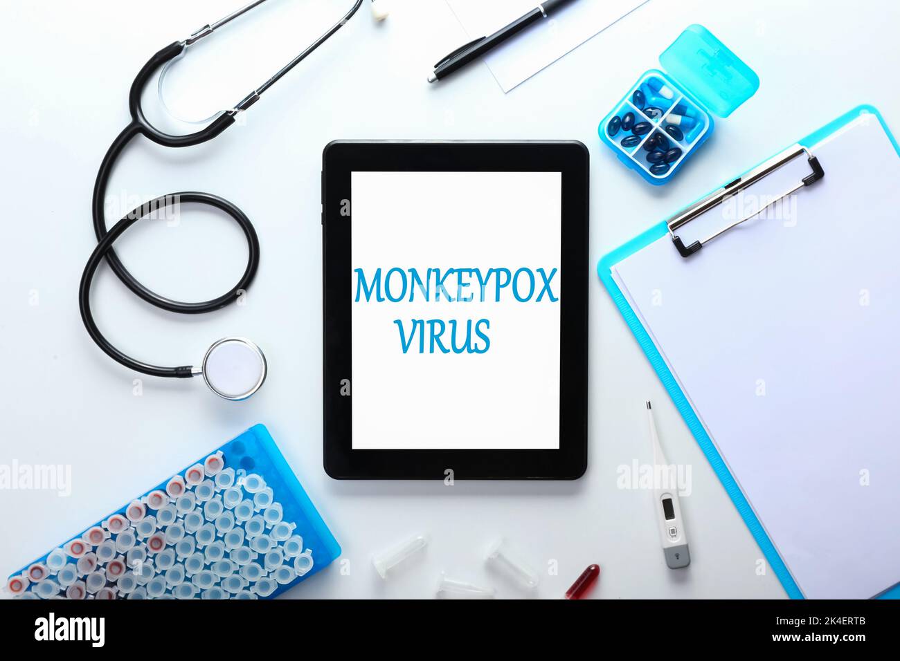 Tablet computer with text MONKEYPOX VIRUS on screen, drugs, test tubes ...