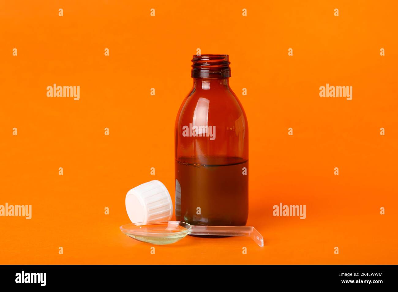 Bottle and spoon of cough syrup on orange background Stock Photo - Alamy