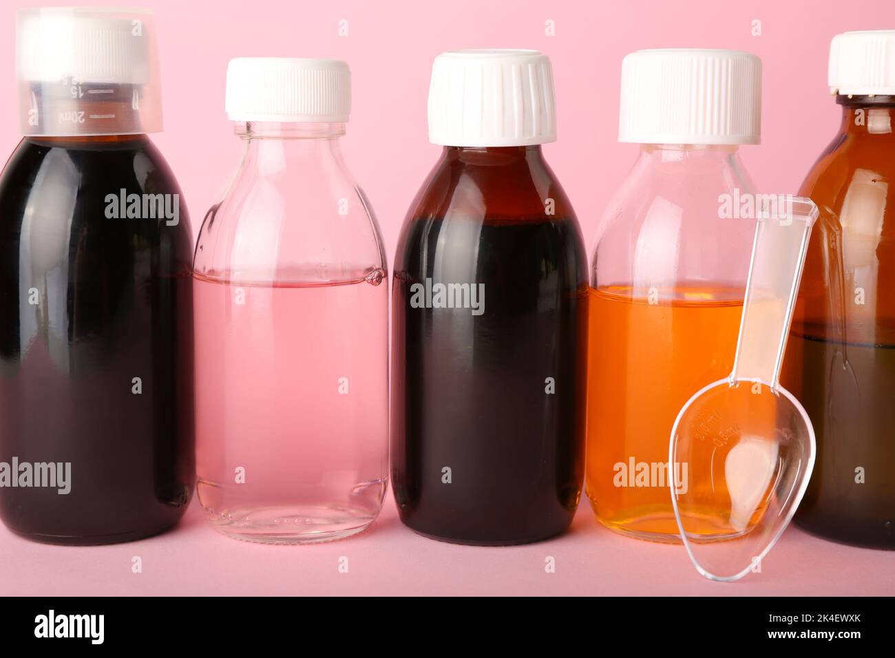 Bottles of cough syrup and spoon on pink background Stock Photo - Alamy