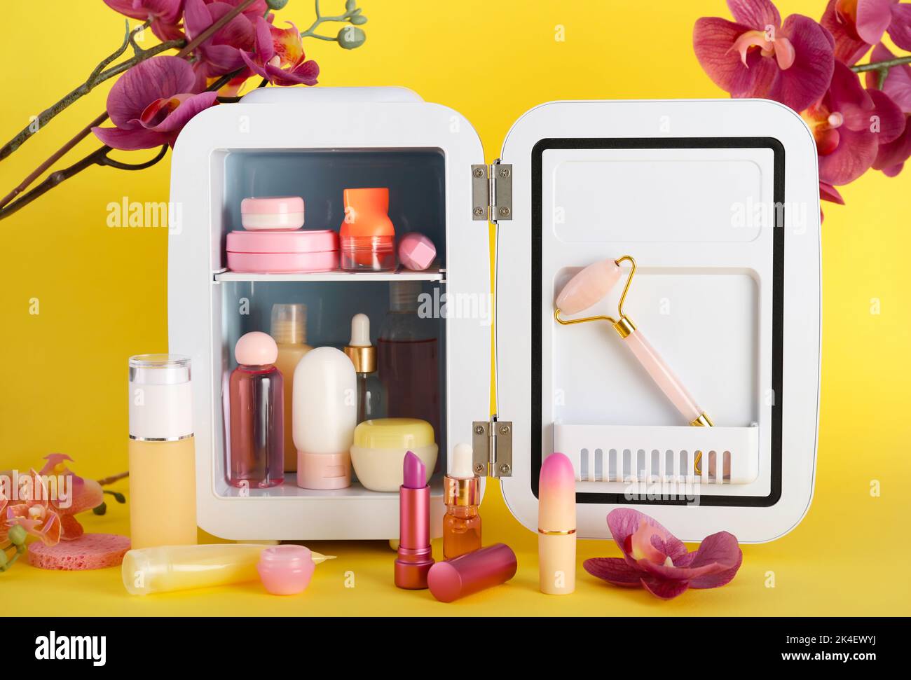 Cosmetic refrigerator with makeup products and flowers on yellow ...