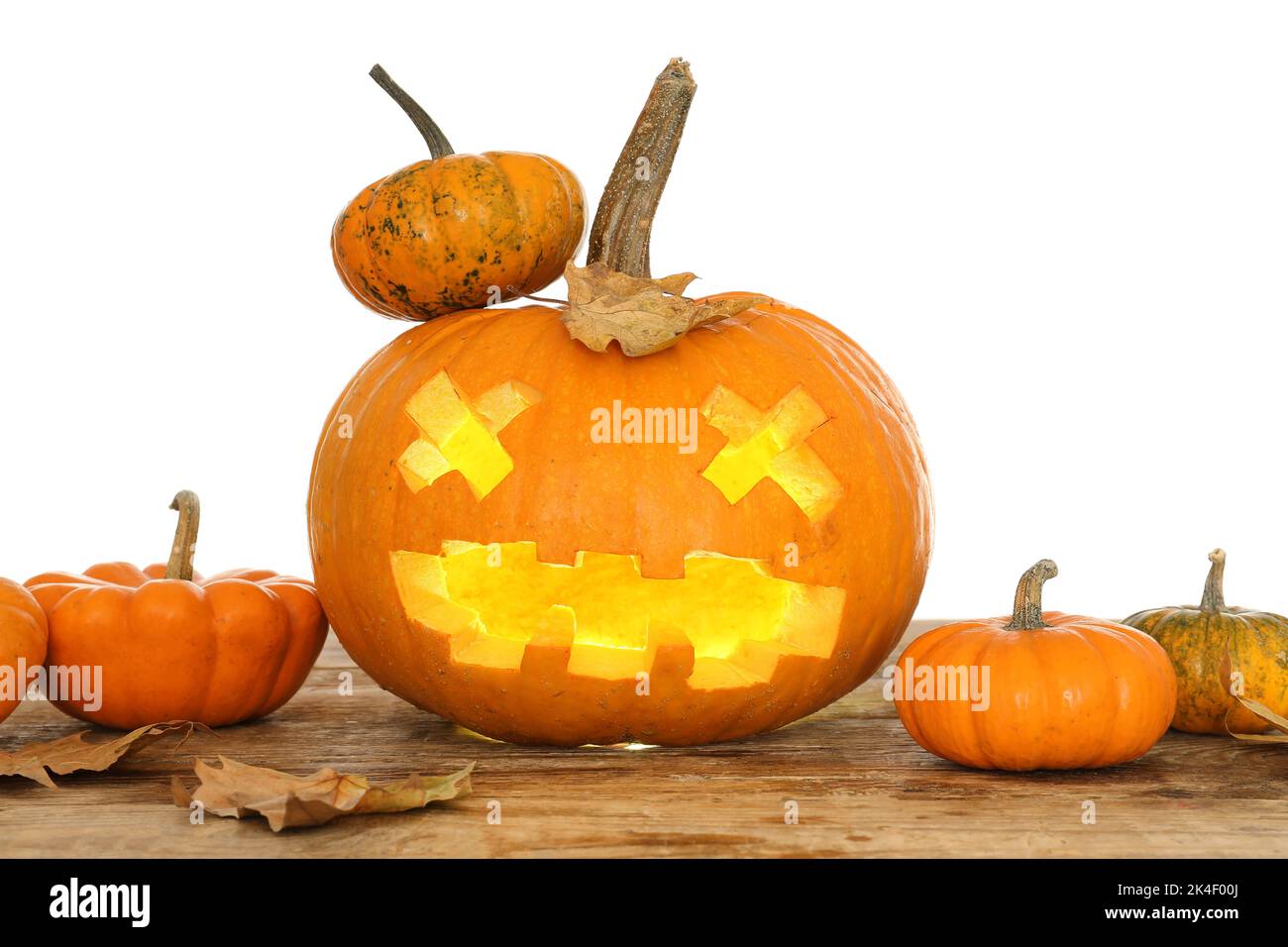 Halloween pumpkins with fallen leaves on table against white background ...