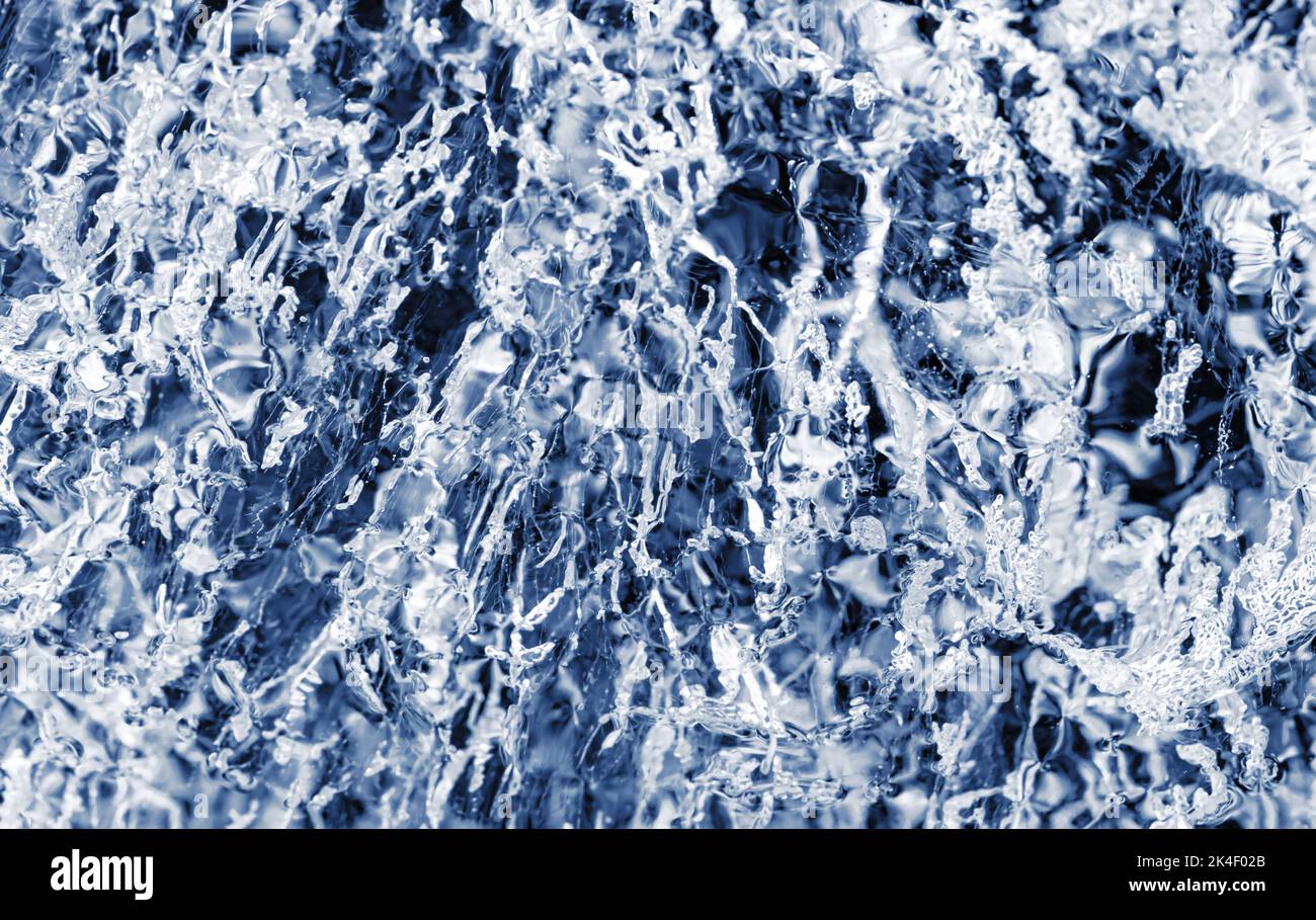 Transparent dark blue ice of frozen Baikal lake with white cracks ...