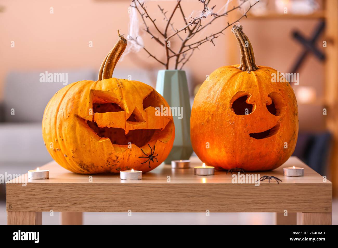 Halloween pumpkins, burning candles and vase with tree branches on ...