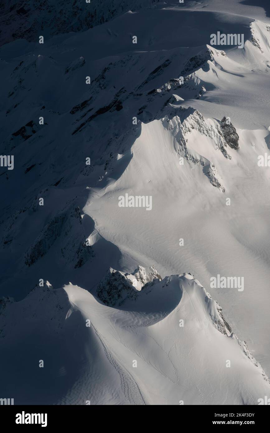 An aerial view of a ridge in the Southern Alps with one side lit by the ...