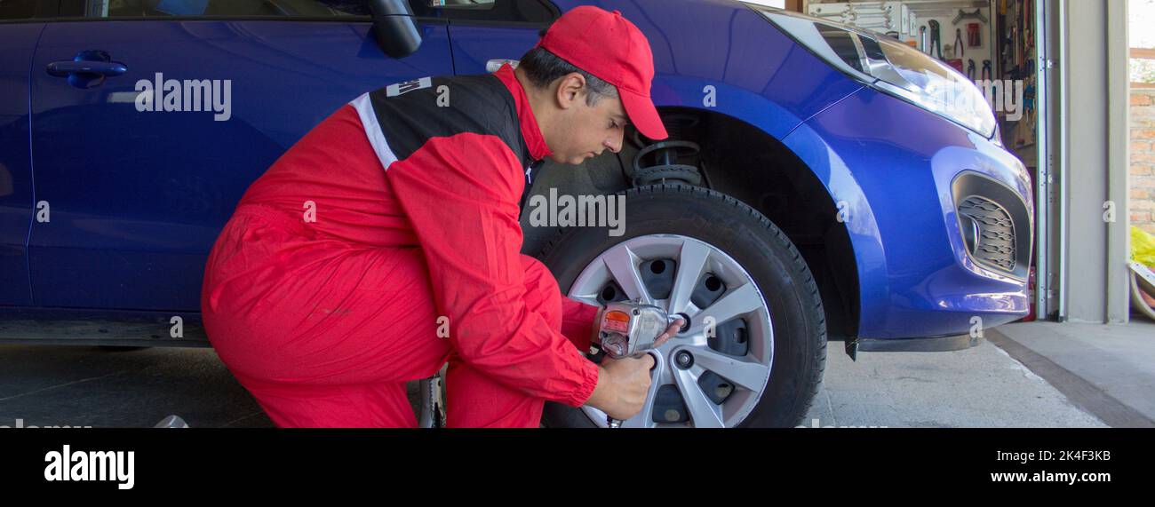 Picture of a mechanic in his workshop who with a pneumatic screwdriver ...