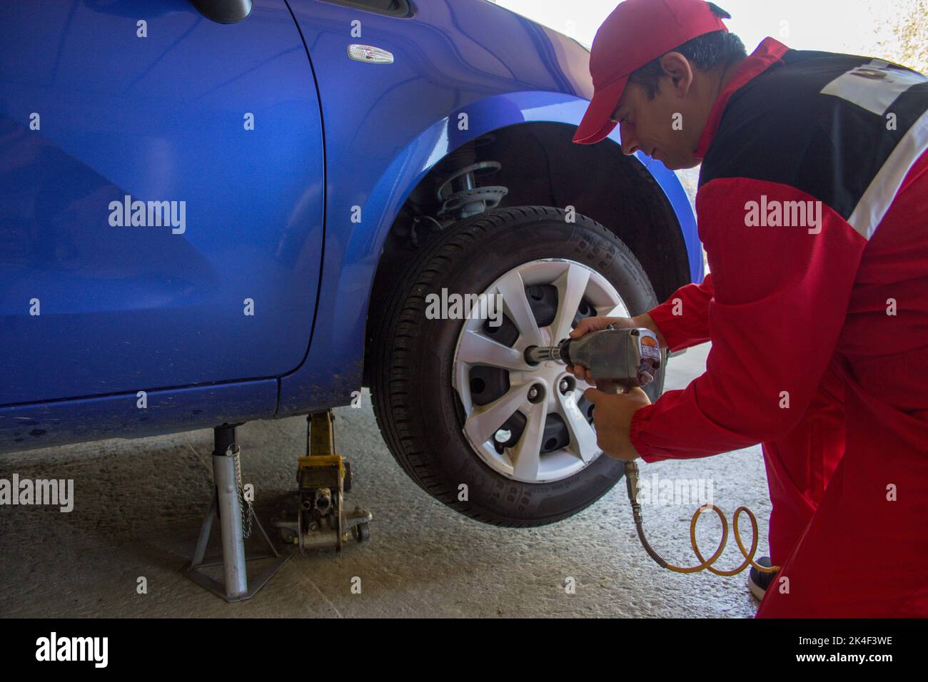 Picture of a mechanic in his workshop who with a pneumatic screwdriver ...