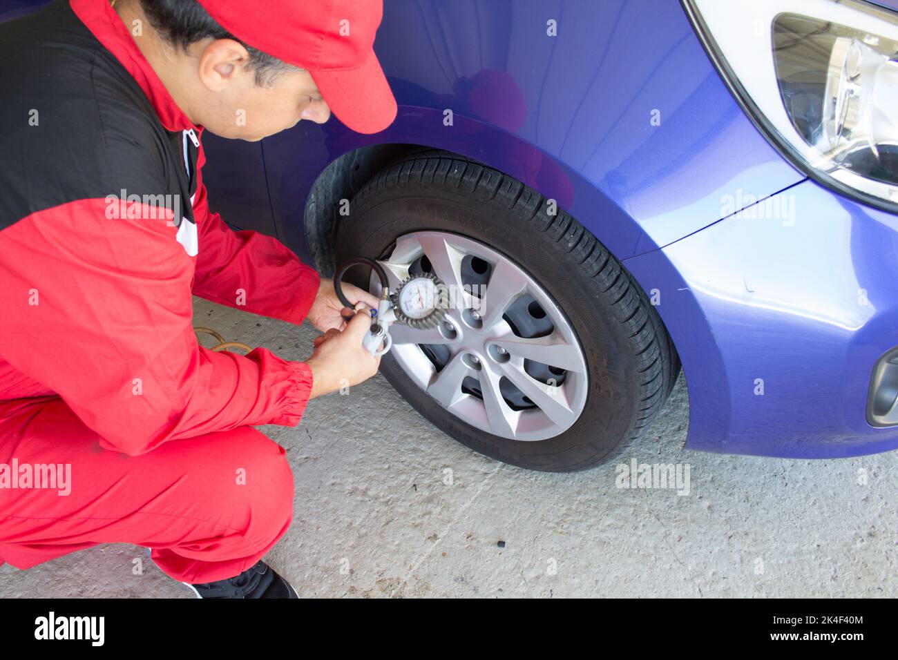 Picture of a mechanic who, with a compressor and a pressure gauge gun ...