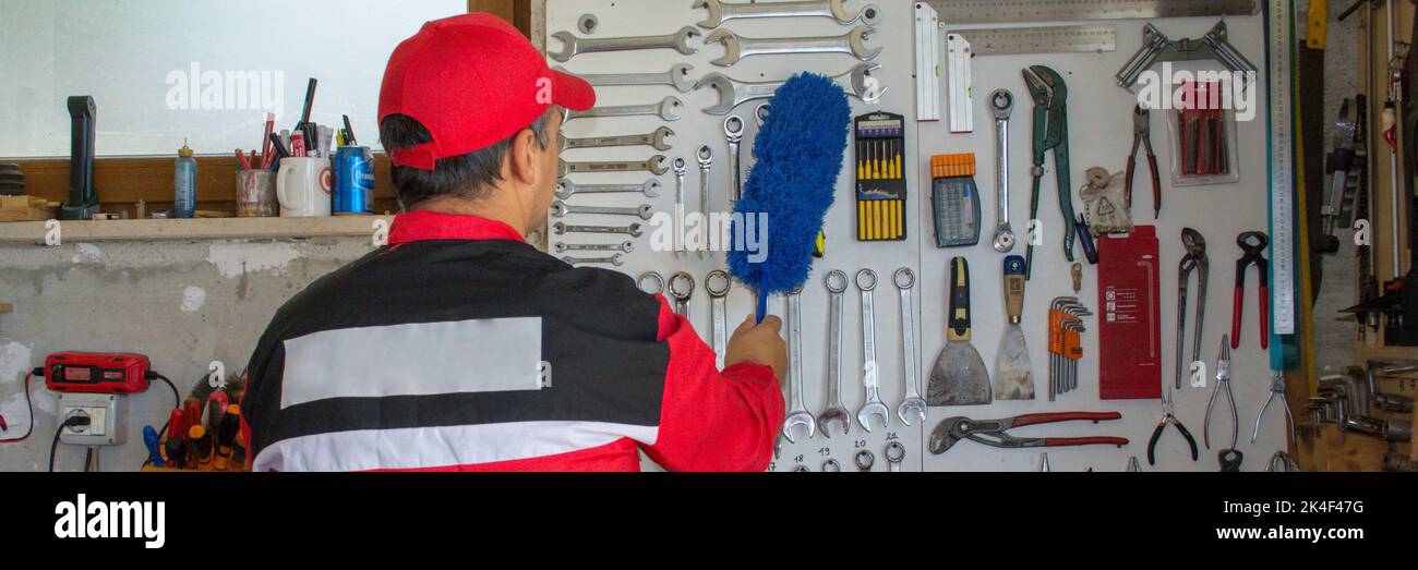 Picture of a mechanic cleaning tools in his workshop with a duster ...