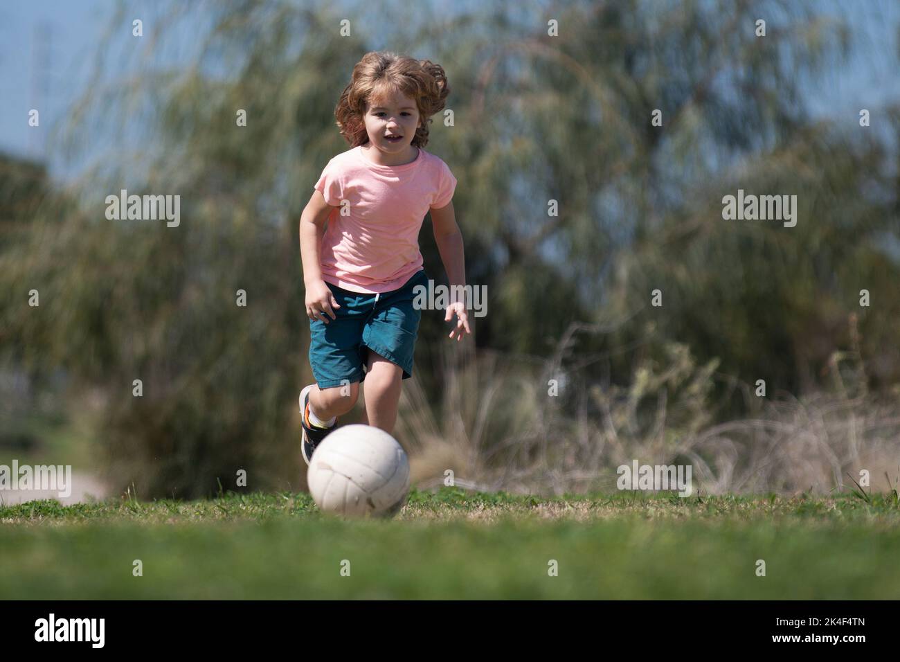 Boy child playing football on football field. Kid playing soccer. Child ...