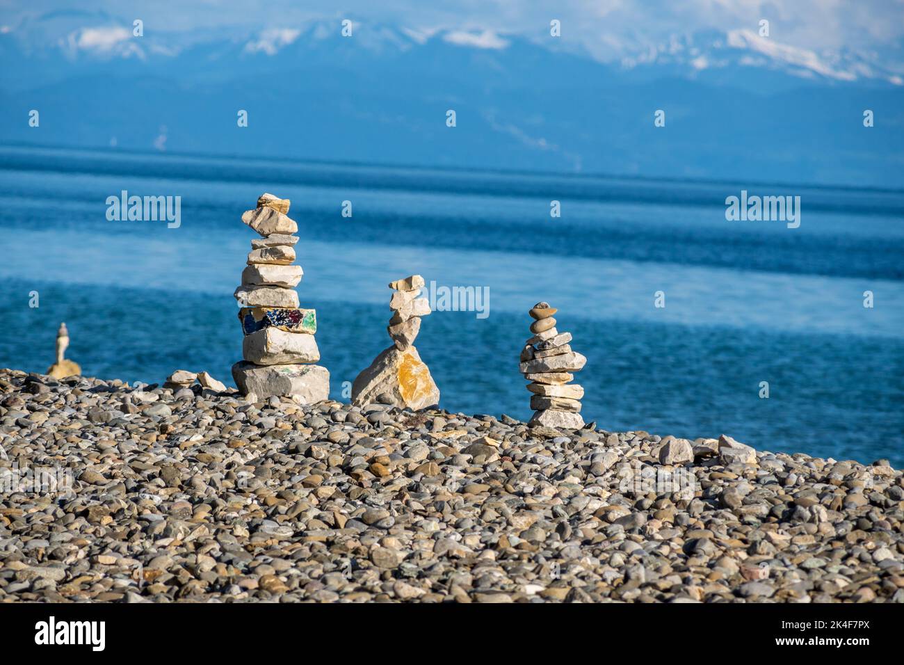 Stone pyramids on the lakeshore with a view of the mountains and sunny ...