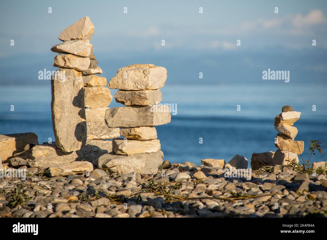 Stone pyramids on the lakeshore with a view of the mountains and sunny ...