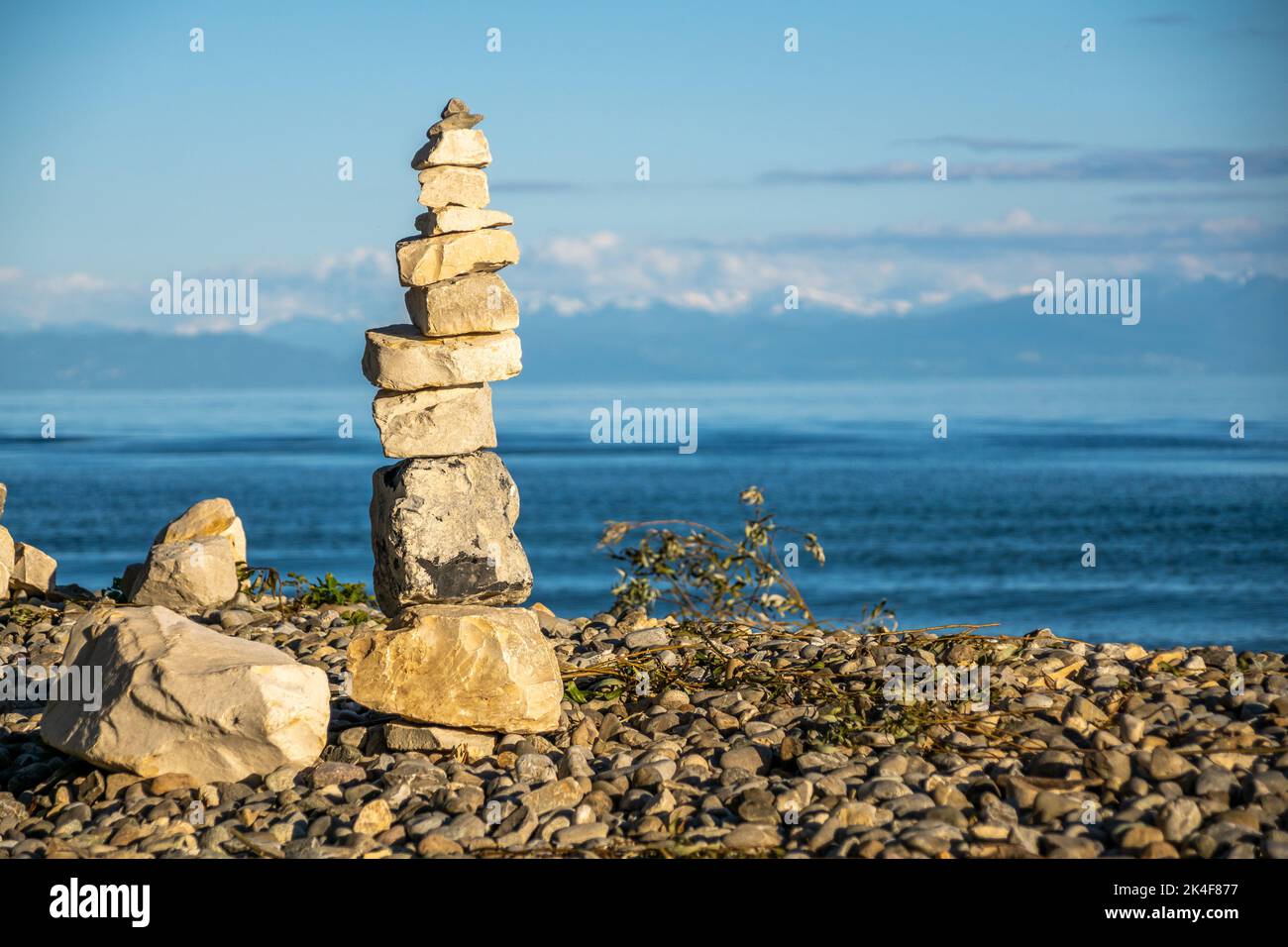 Stone pyramids on the lakeshore with a view of the mountains and sunny ...