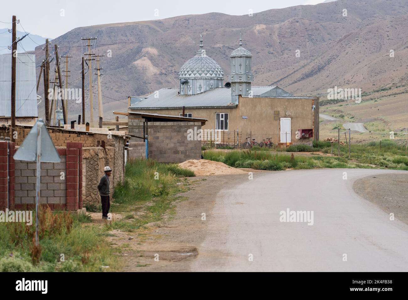 Mosque and man in traditional hat in remote village on the way to Song ...