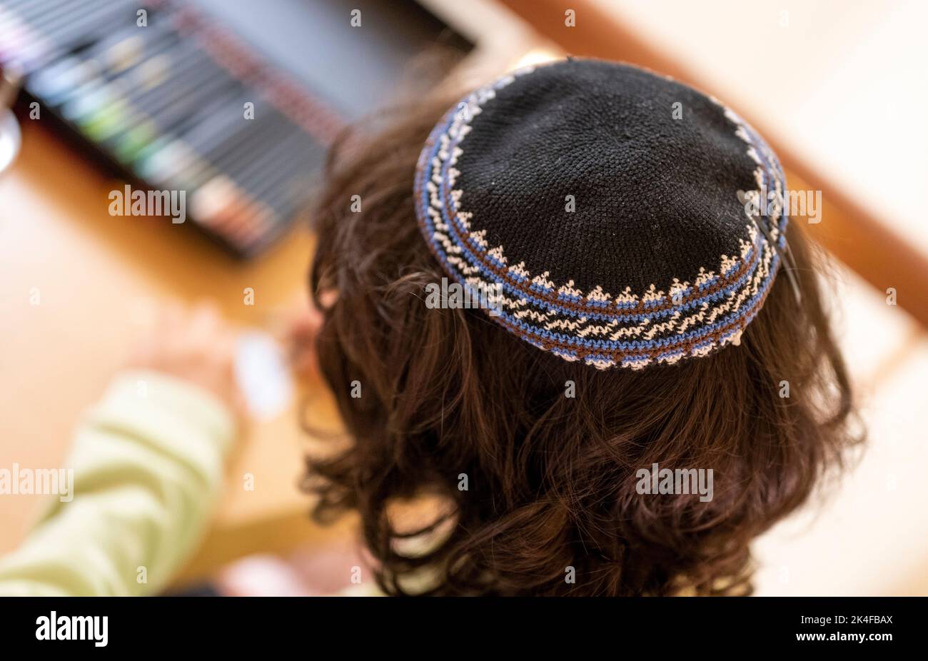 Potsdam, Germany. 02nd Oct, 2022. A boy with a kippah on his head sits at a craft booth at the ...
