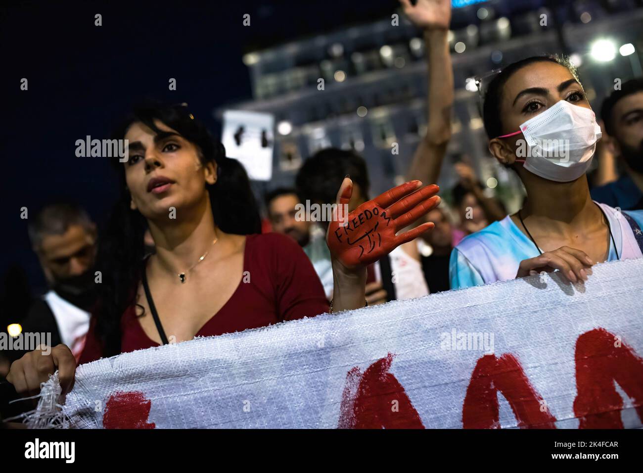 A protester holding a banner displays her hand painted in red with a ...