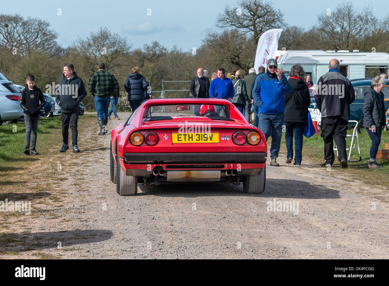 A rear view of a 1980 Ferrari 308 GTS driving slowly along a hardpacked ...