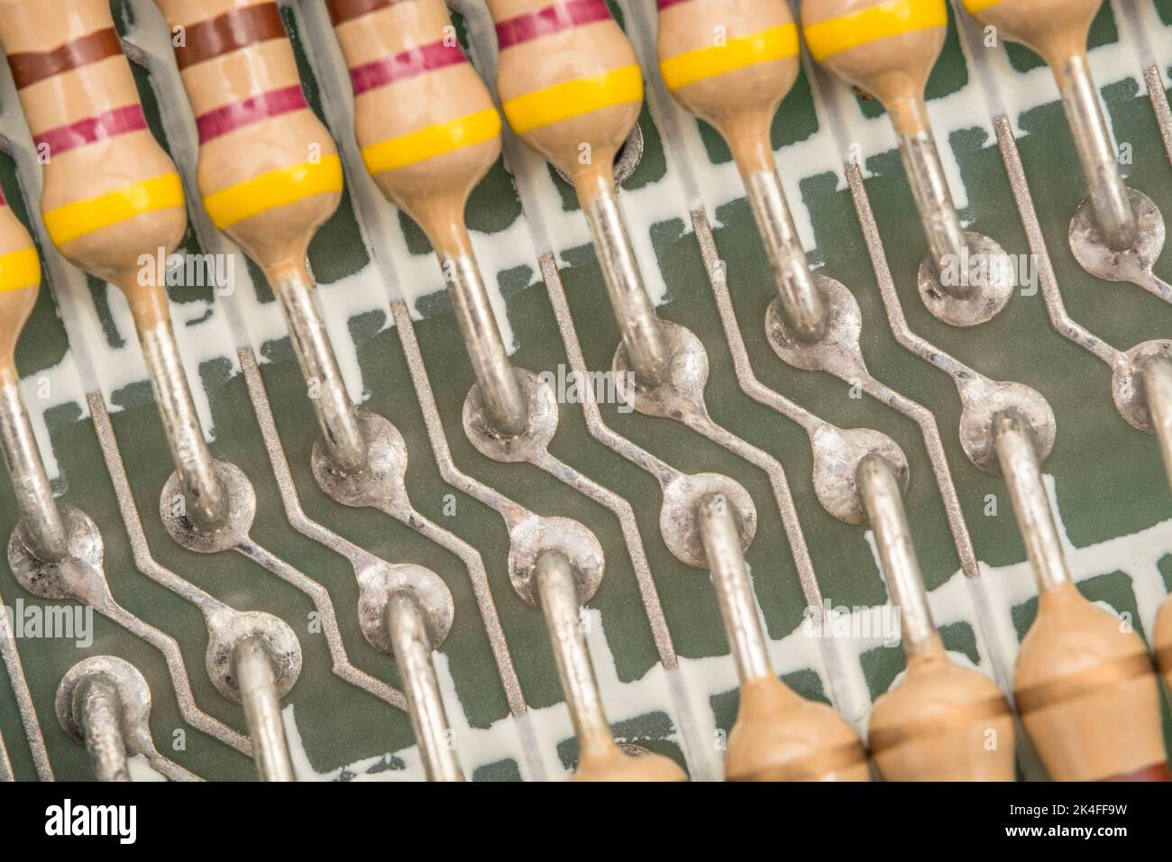 Row of carbon film resistors and soldered lead contacts on the PCB ...