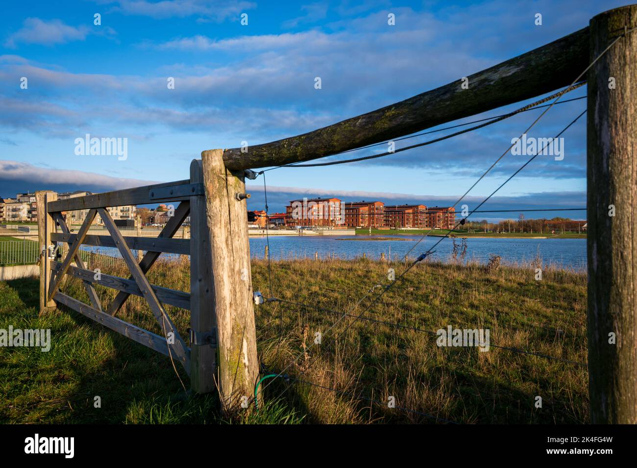 Rural fence and gate close to lake and the city of Lund Sweden beyond ...