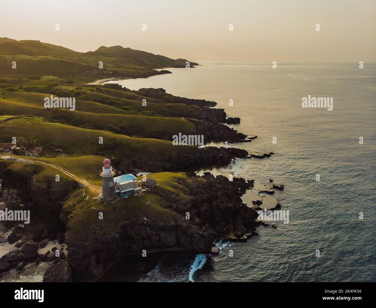 A beautiful view of green hills and the beach at sunset on Batanes ...