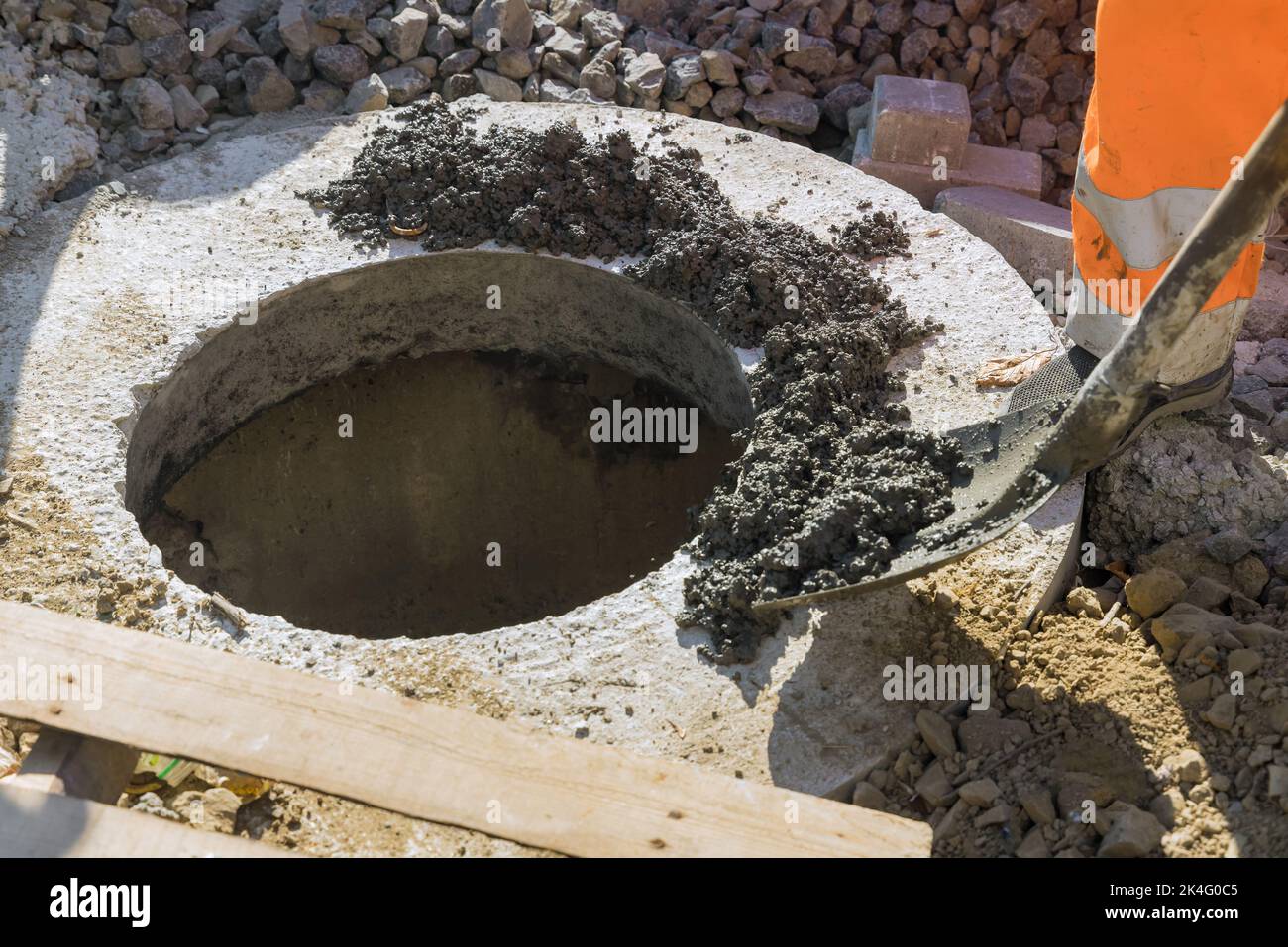 At a construction site, a cast-iron sewer hatch is being installed on a ...