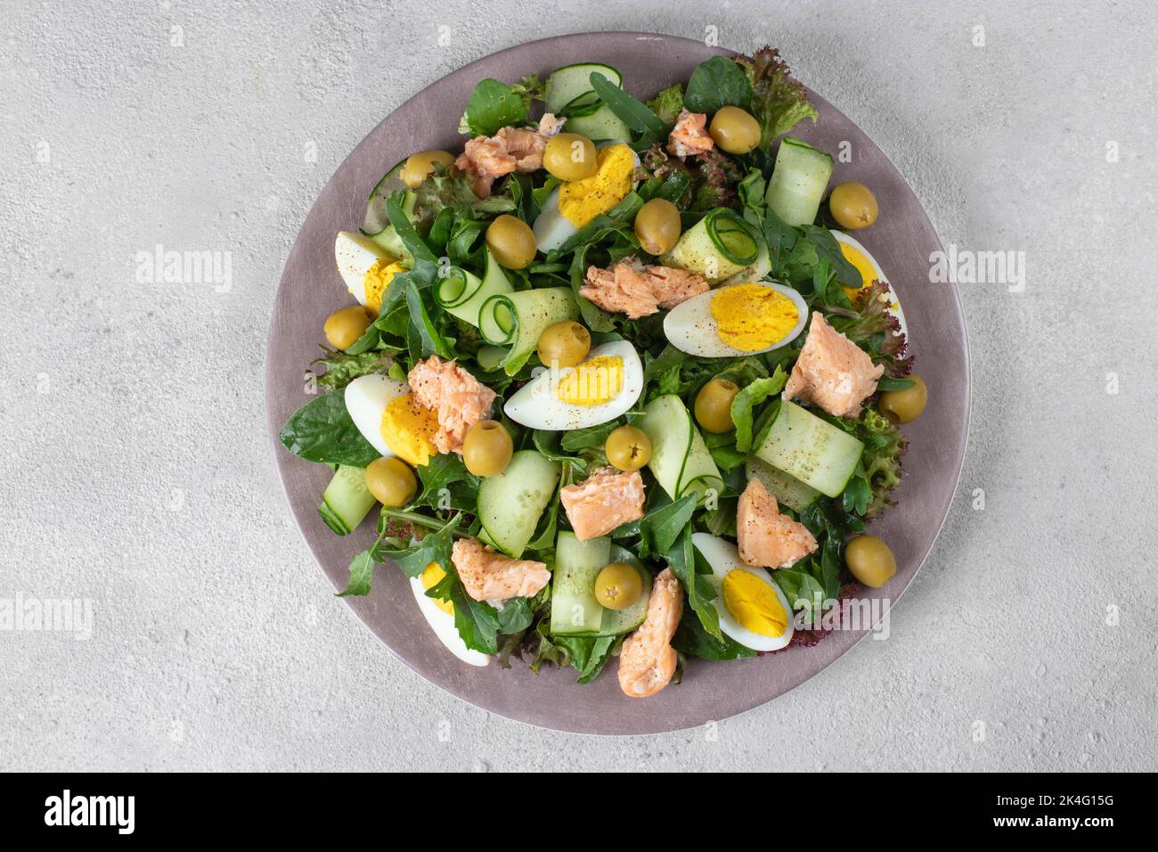 Salad with canned salmon, egg, cucumber, olives and arugula on round ...