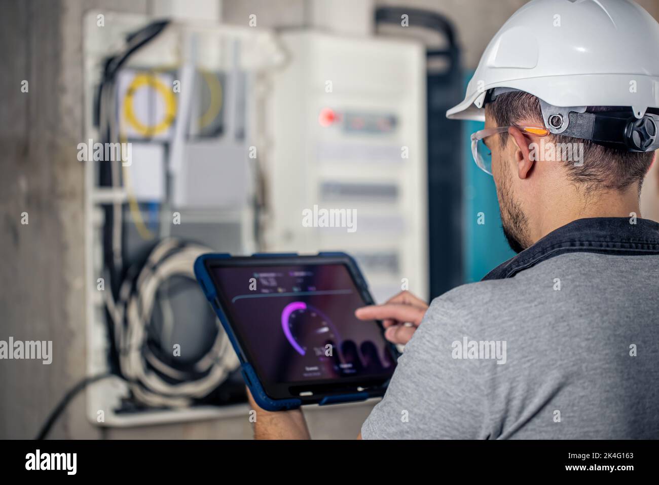 Man, an electrical technician working in a switchboard with fuses, uses ...