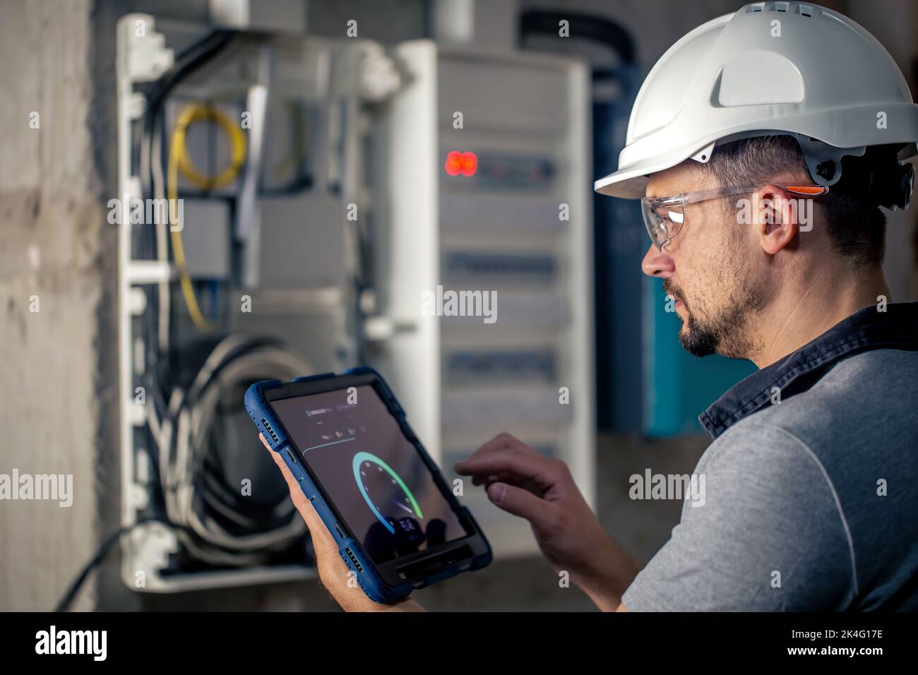 Man, an electrical technician working in a switchboard with fuses, uses ...
