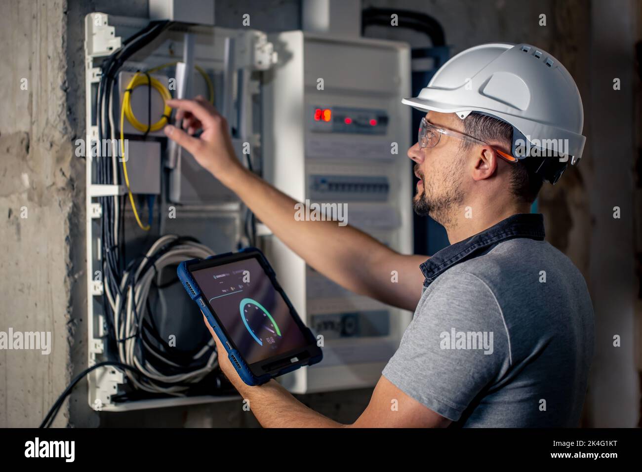 Man, an electrical technician working in a switchboard with fuses, uses ...