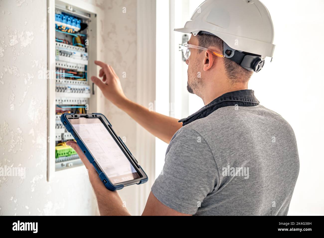 Man, an electrical technician working in a switchboard with fuses, uses ...